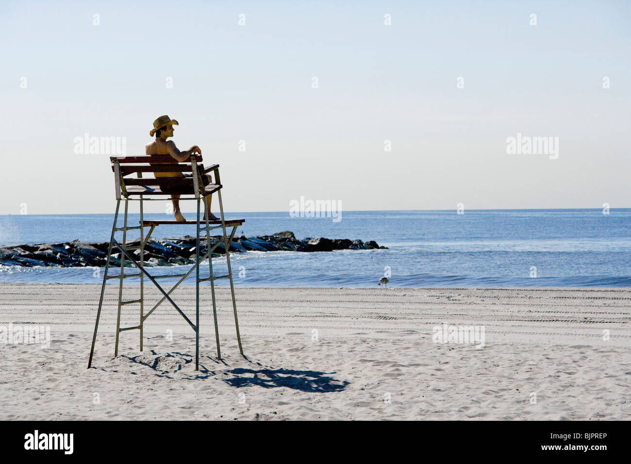 Man sitting in lifeguard chair at beach Stock Photo - Alamy
