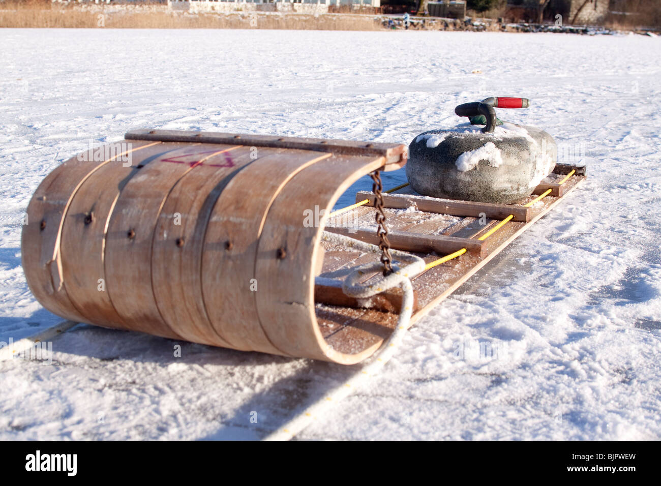 Curling stones on wooden sled on frozen lake Stock Photo - Alamy