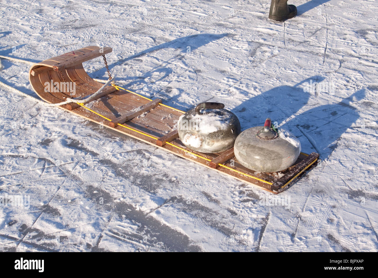 Curling stones on wooden sled on frozen lake Stock Photo - Alamy