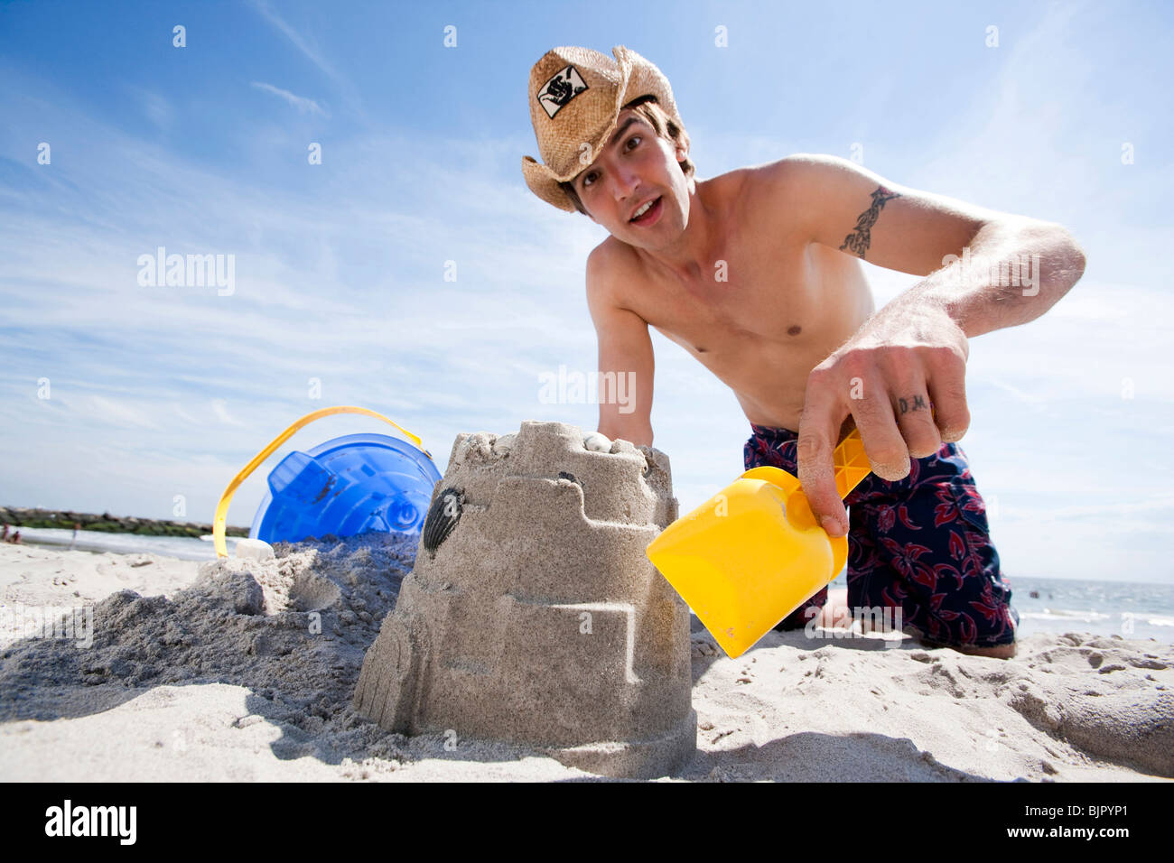 Man building a sand castle at the beach Stock Photo - Alamy