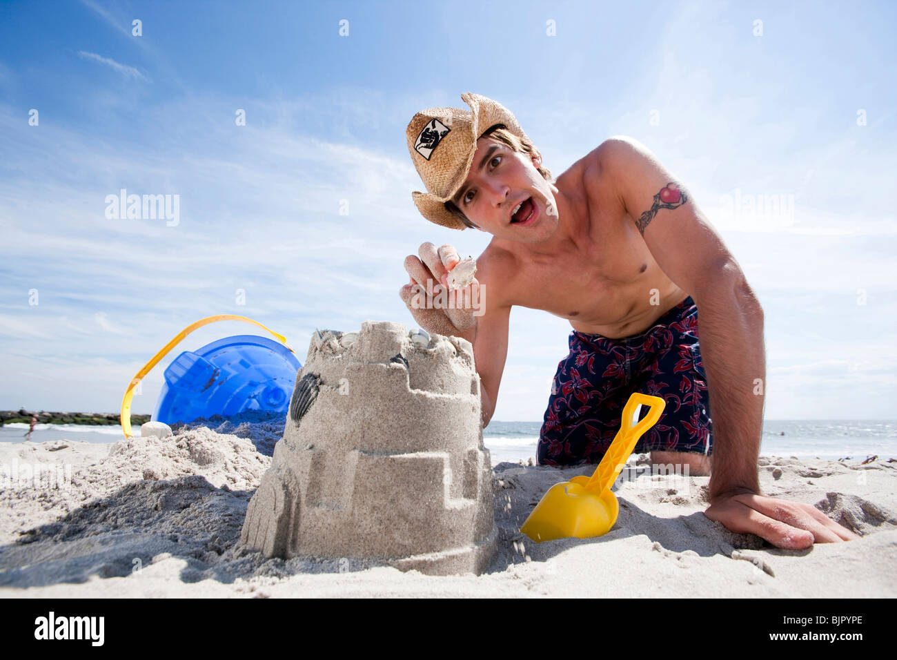 Man building a sand castle at the beach Stock Photo - Alamy