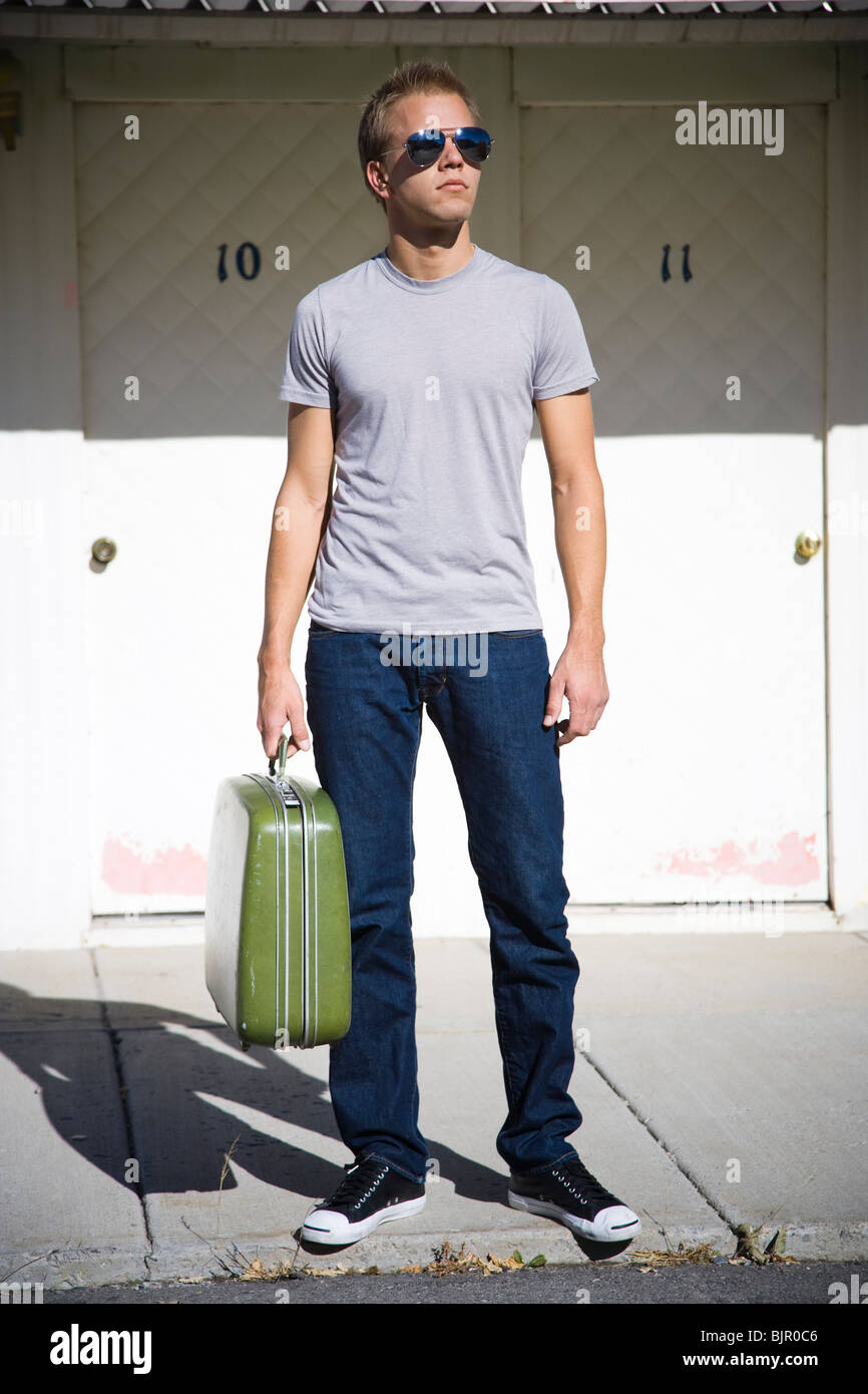 Young man standing with a suitcase Stock Photo - Alamy