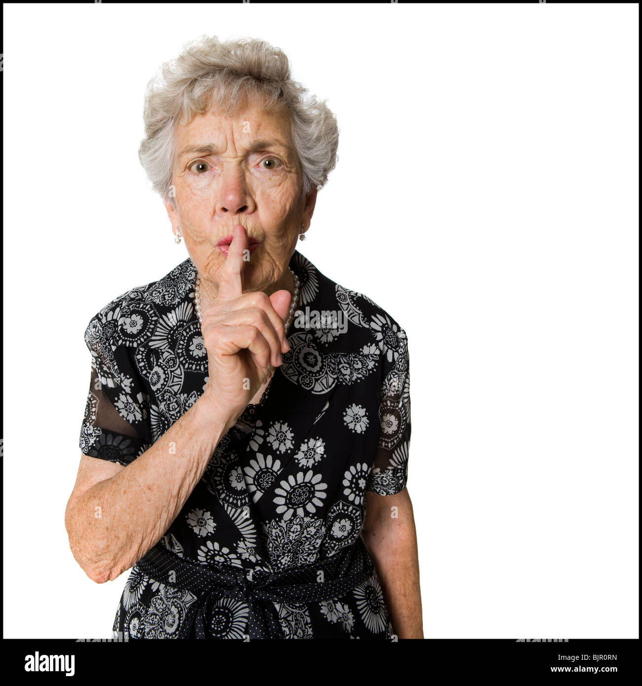 Senior woman shushing camera Stock Photo - Alamy