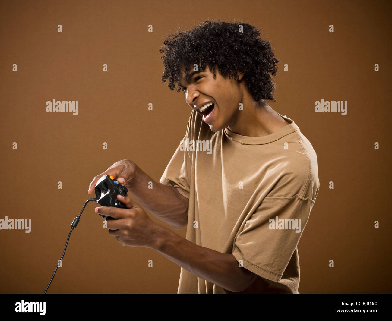 young man in a brown shirt playing a video game Stock Photo - Alamy
