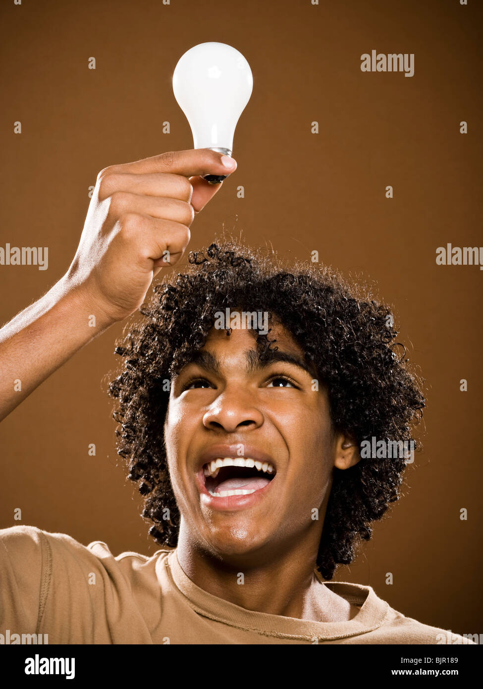 young man in a brown shirt holding light bulbs Stock Photo - Alamy