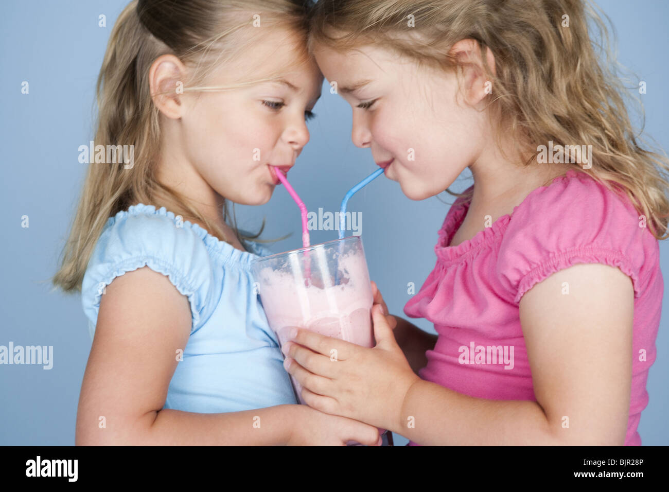 Two girls sharing a milkshake Stock Photo - Alamy