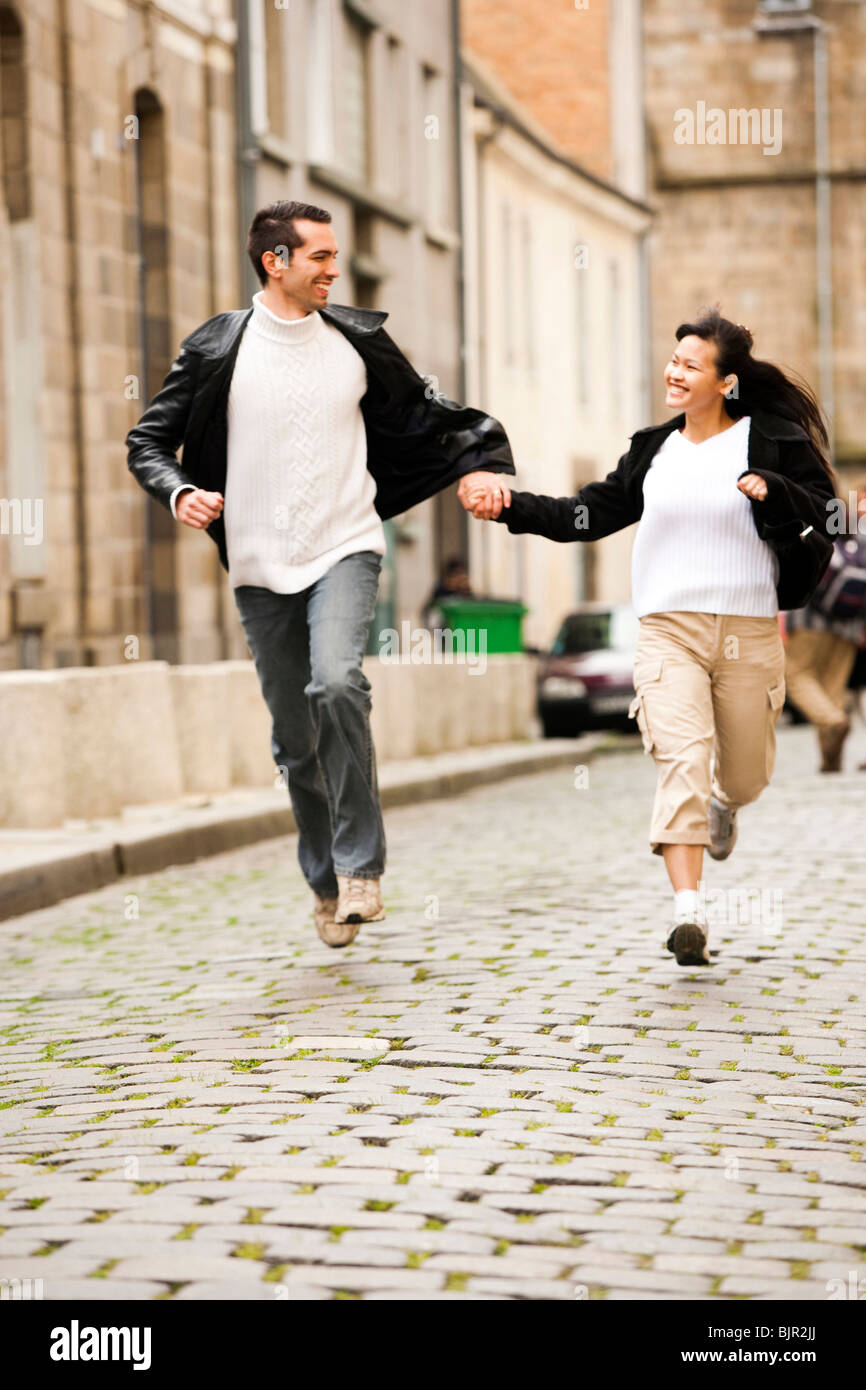 Couple skipping down the street Stock Photo - Alamy