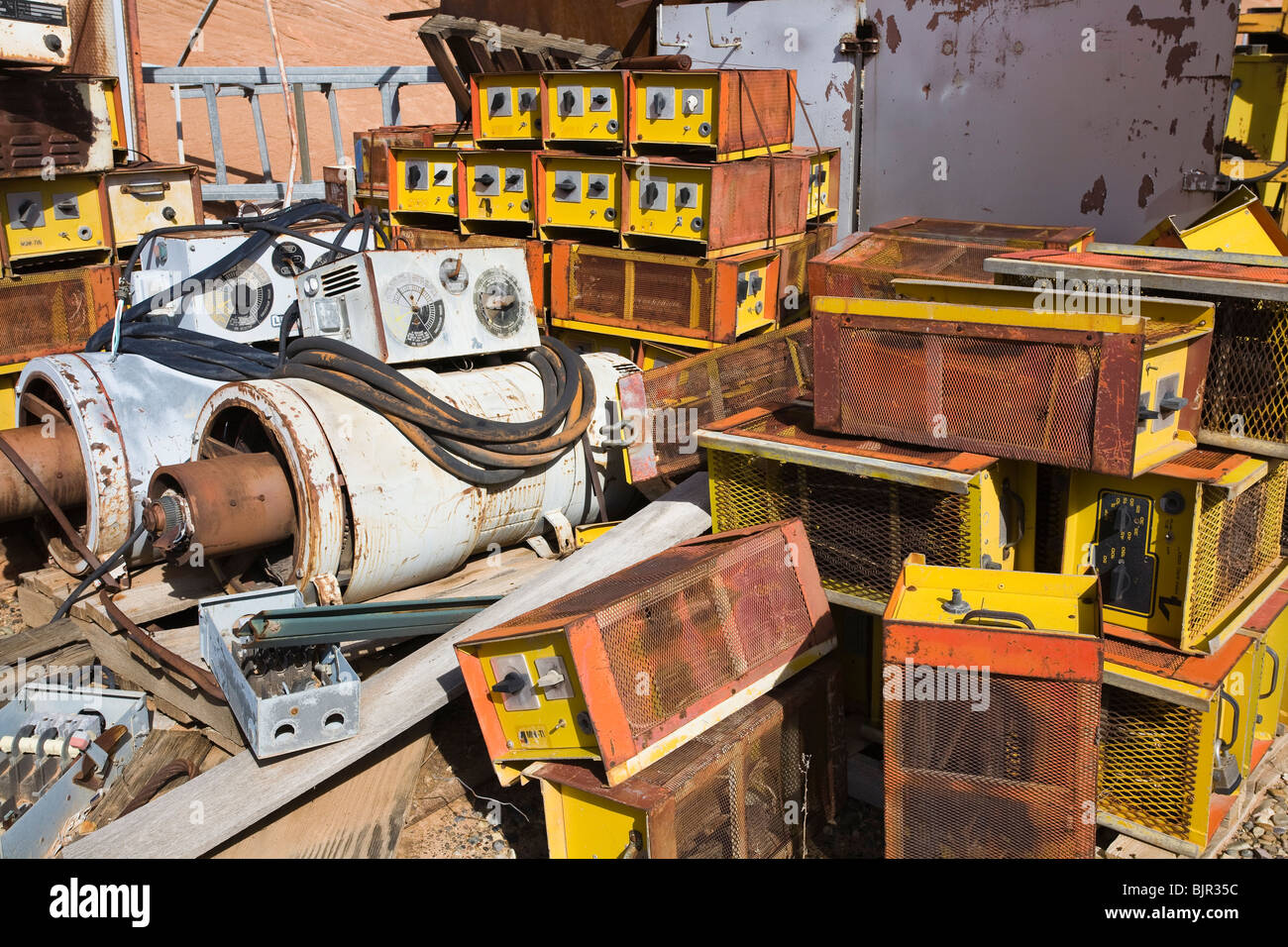 Group of old, rusty yellow welding machines stacked at a scrap metal ...