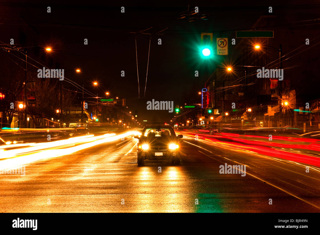This is an image of a car in the middle of a busy intersection at night ...