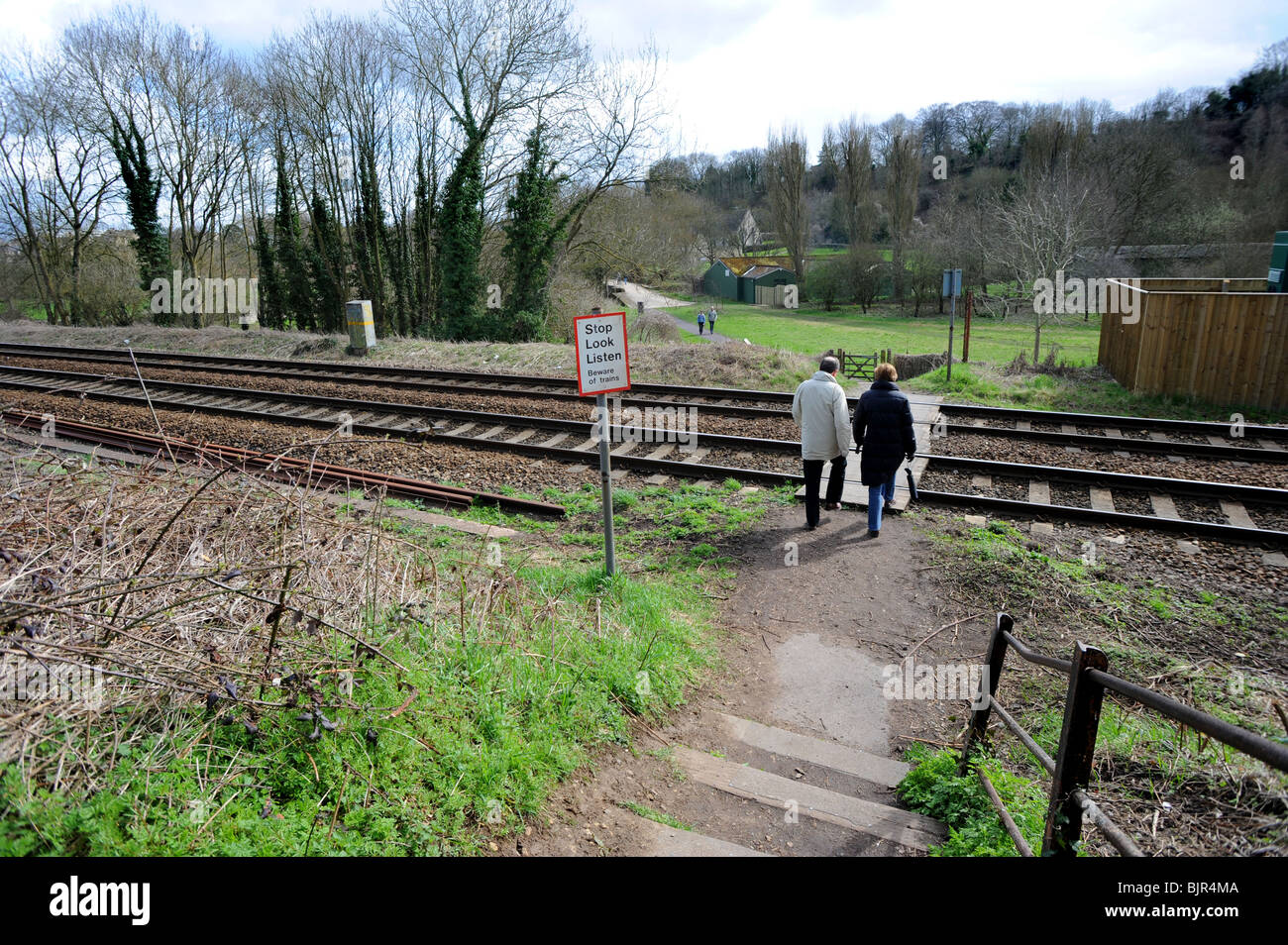 A couple walk over the railway lines at a quiet crossing point in the ...