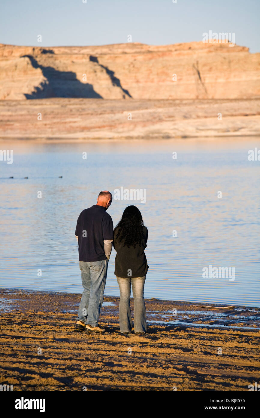 Couple walking along the shore of Lake Powell, near Utah, Arizona state ...