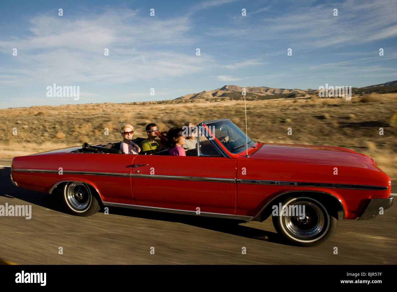 red car driving down the road Stock Photo - Alamy