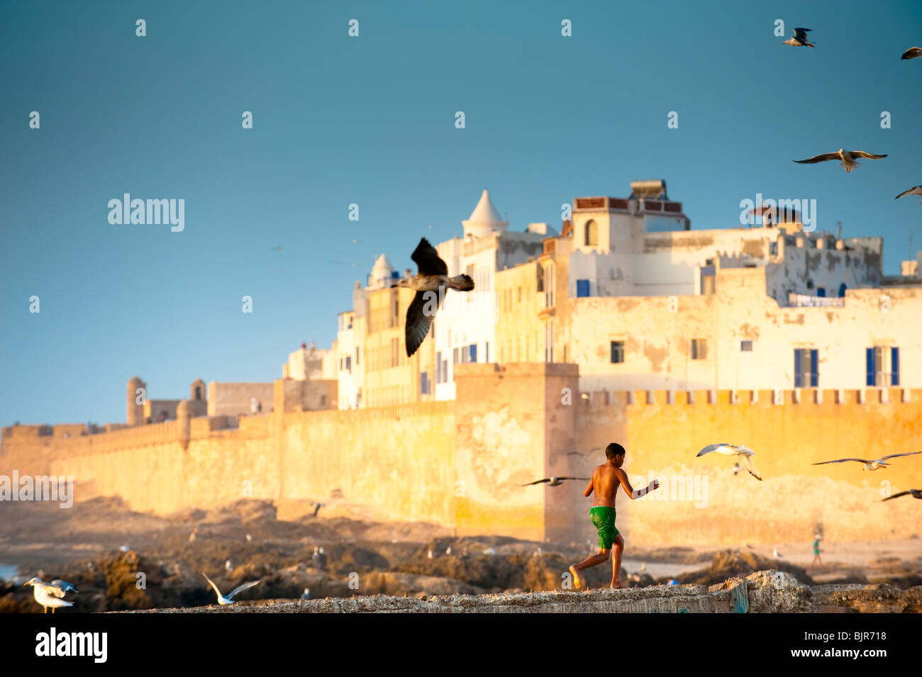 This is an image of a Moroccan boy running along the old city walls of ...