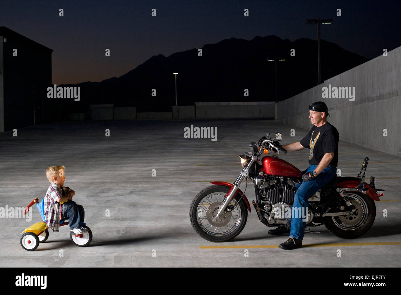 boy on a tricycle next to a man on a motorcycle Stock Photo - Alamy