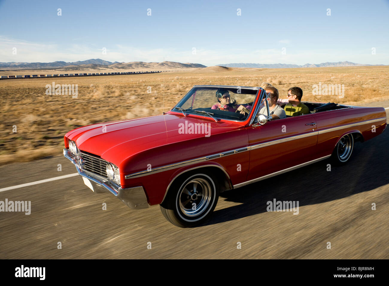 red car driving down the road Stock Photo - Alamy