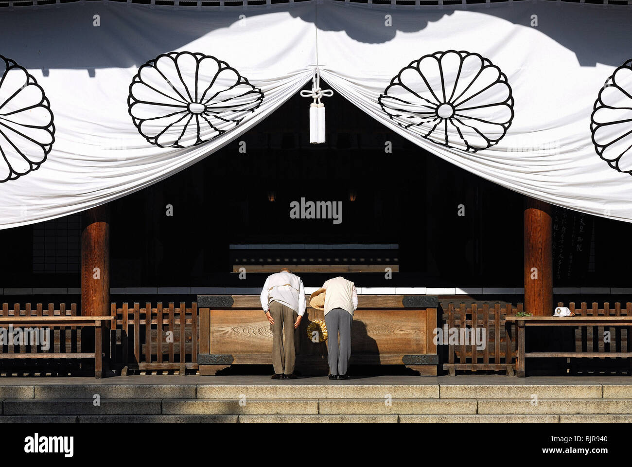 couple bows during prayer at the main hall of Yasukuni Shrine in Tokyo ...