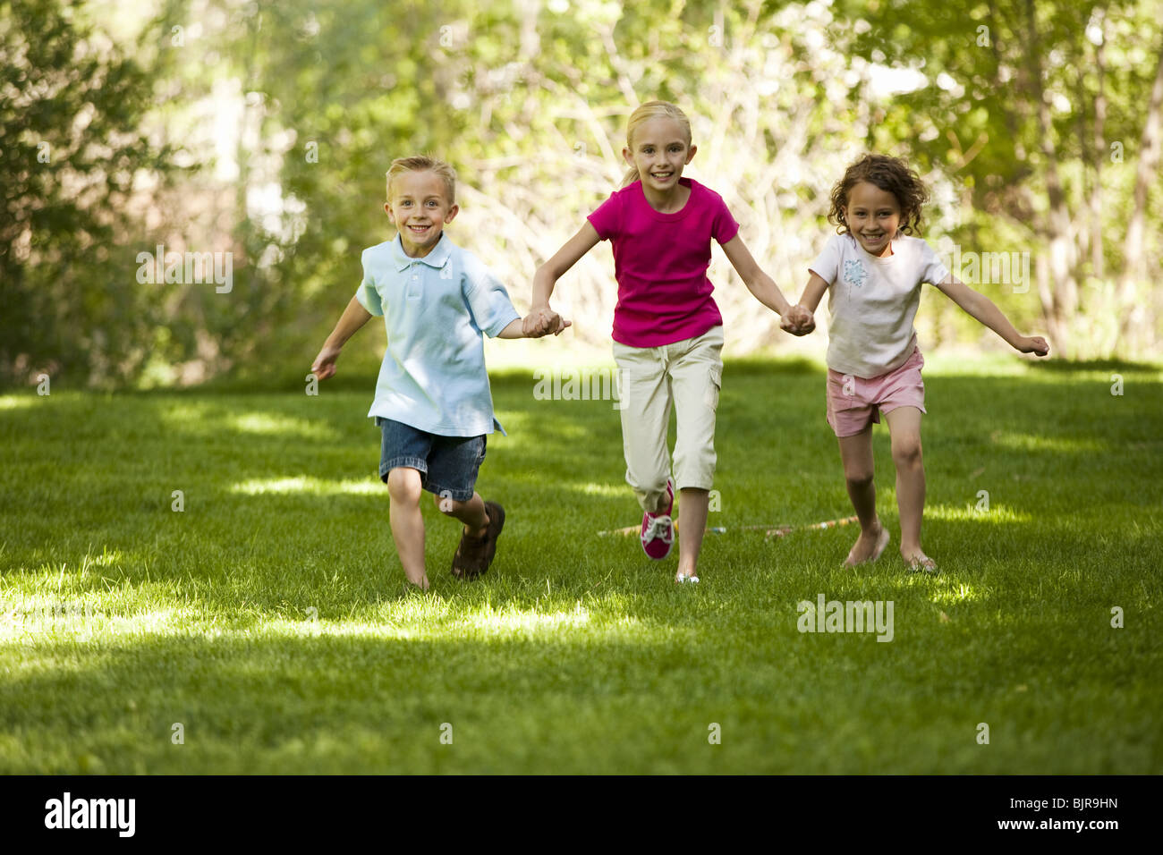 Three children running in park Stock Photo - Alamy