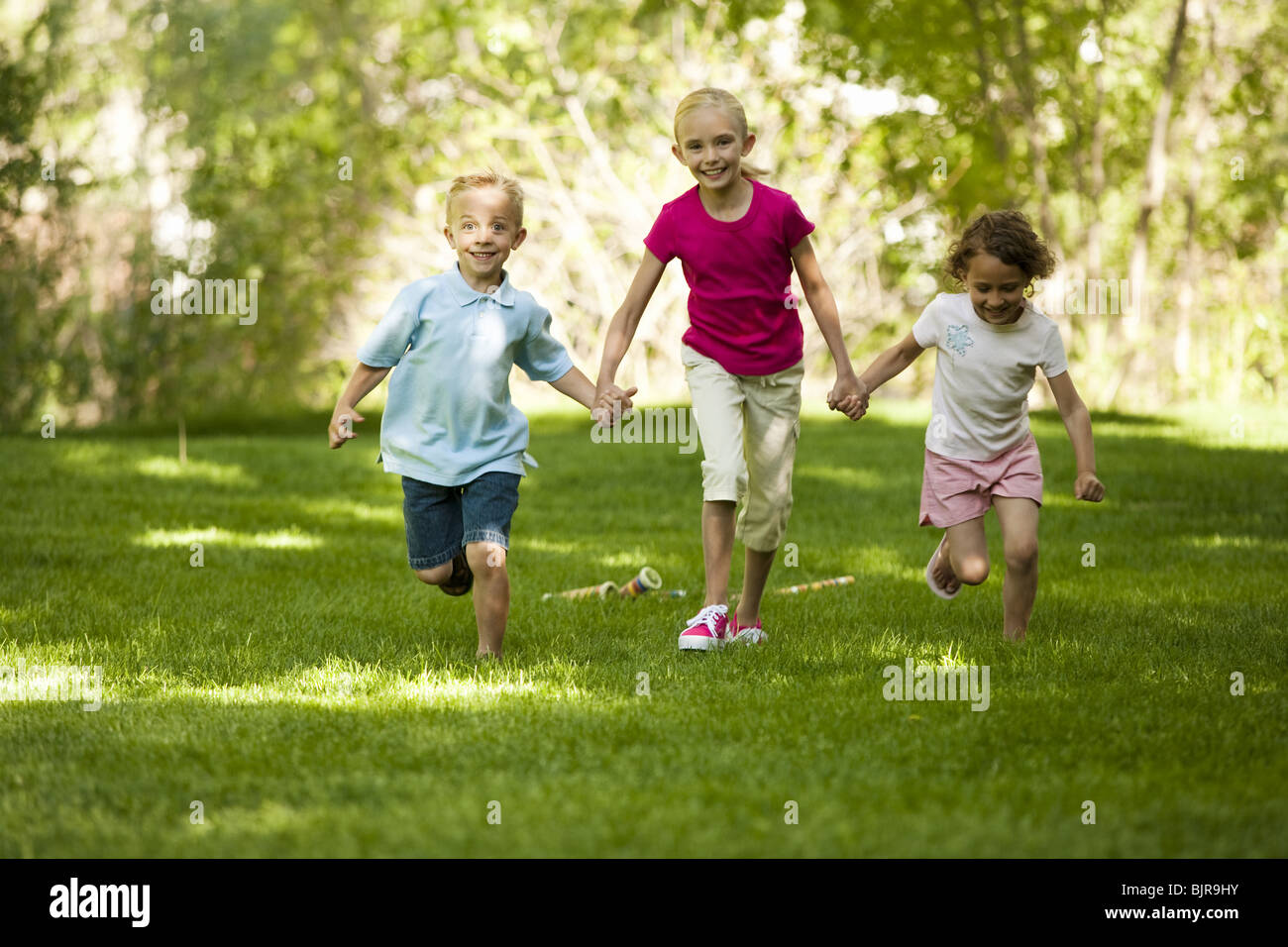 Three children running in park Stock Photo - Alamy