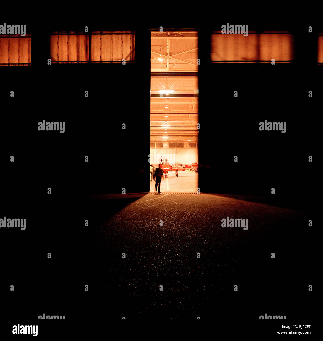 Lone figure stands silhouetted against hangar lights of aerobatic team ...