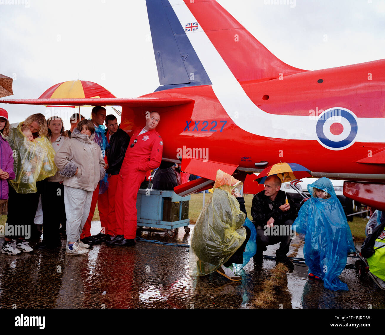 Red Arrows pilots shelter from rain storm under tail of a BAE Systems ...