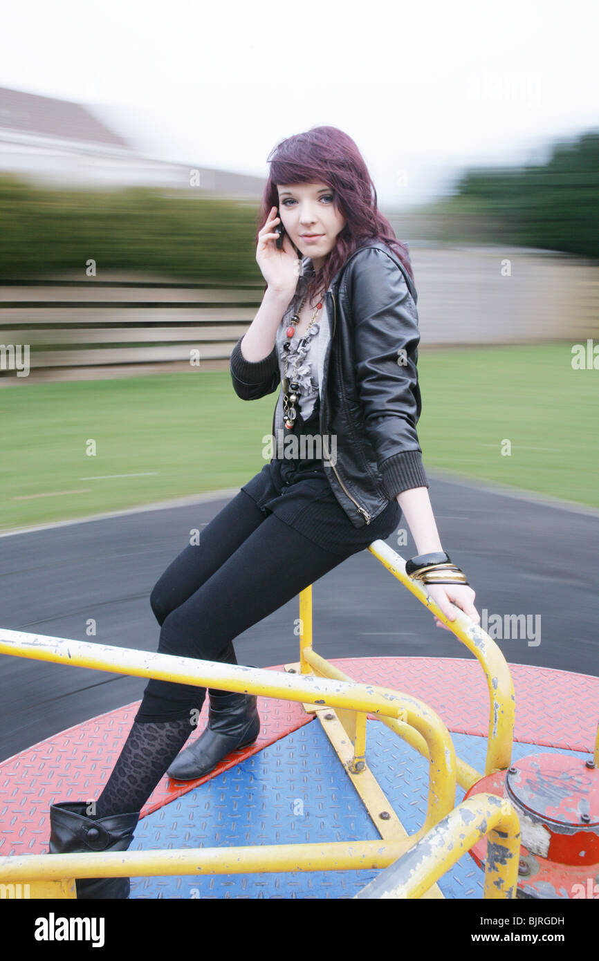Teenage girl sitting on a roundabout talking on her mobile phone Stock ...