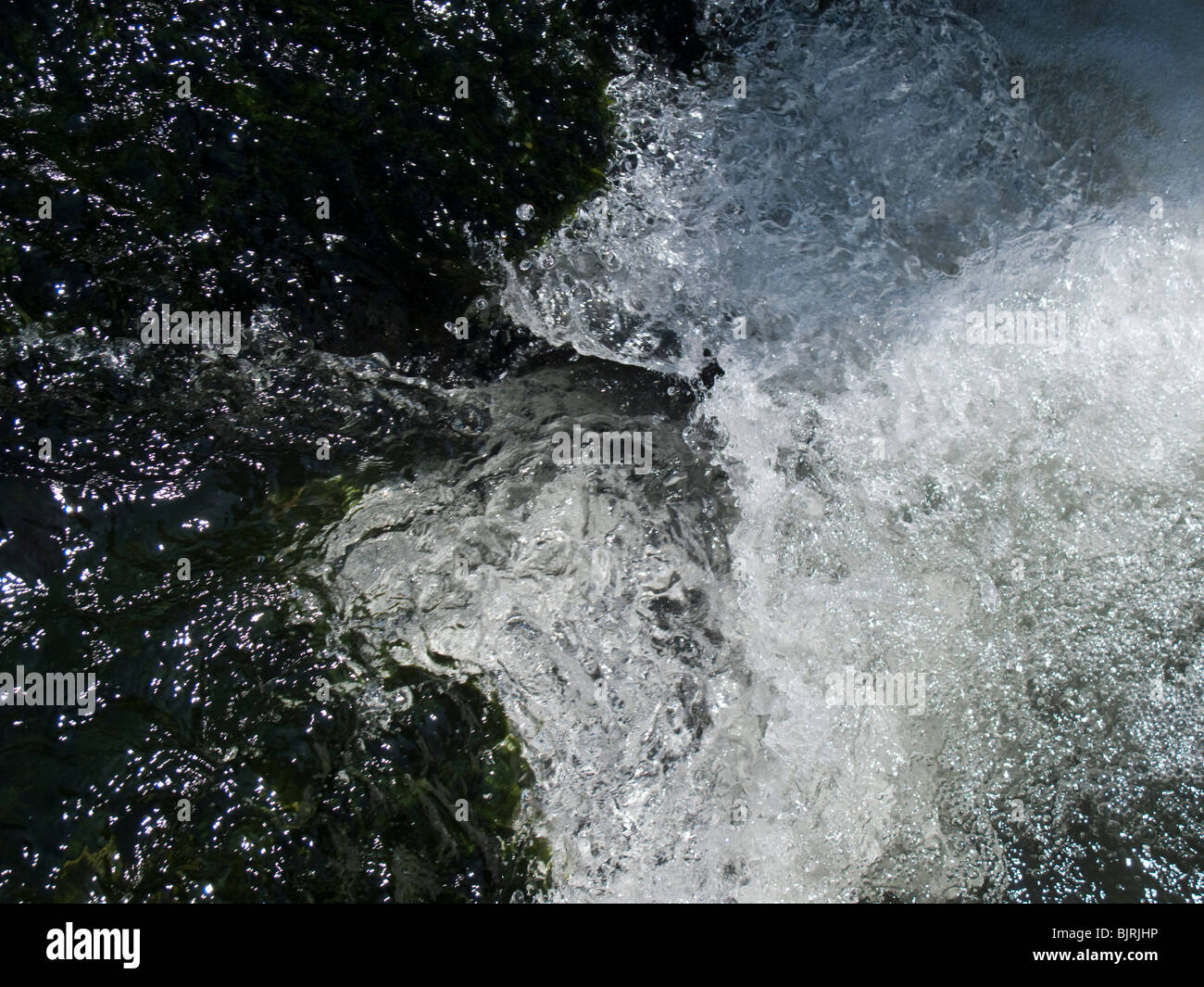 splashing sea water around rocks on a beach Stock Photo - Alamy