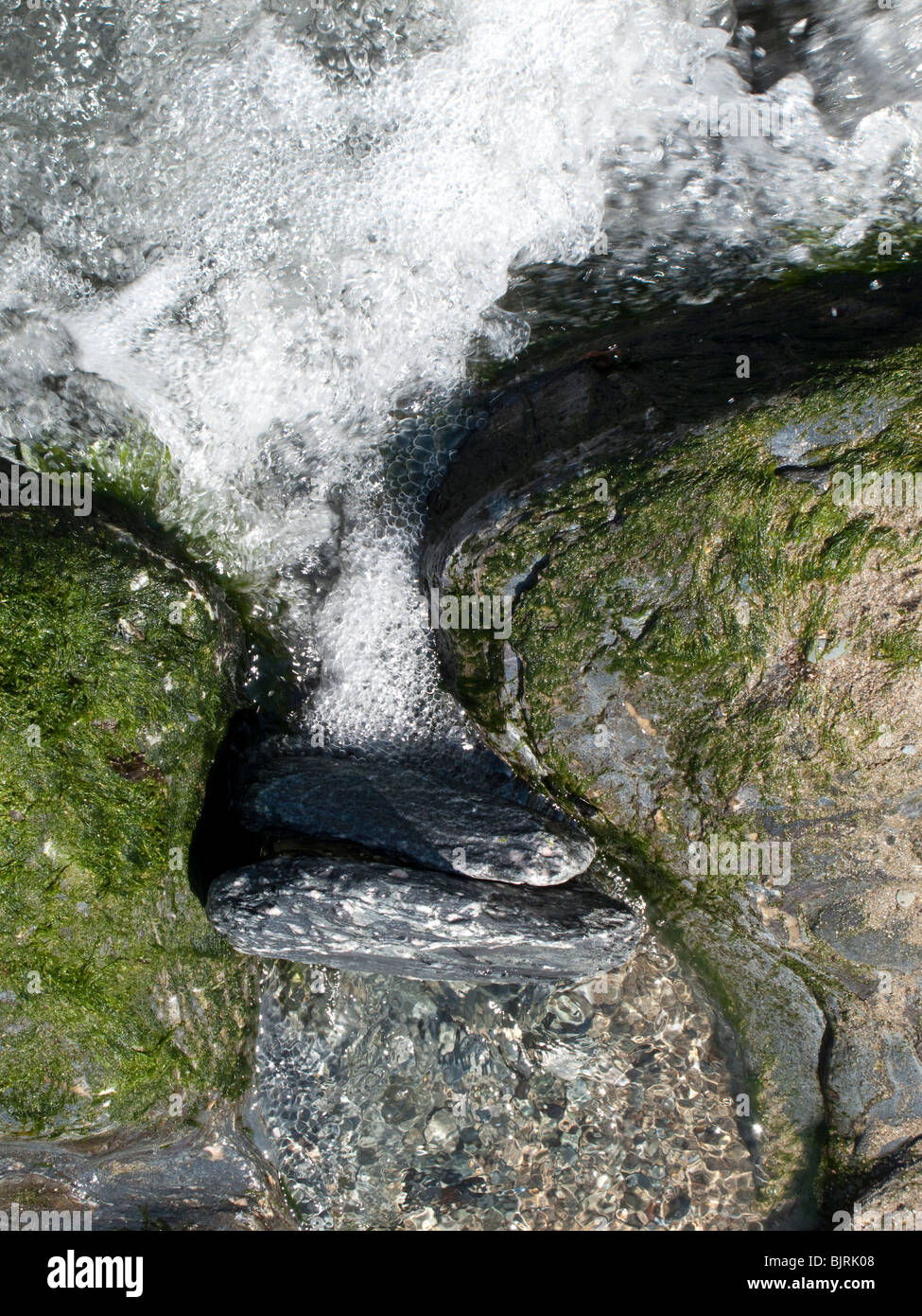 splashing sea water around rocks on a beach Stock Photo - Alamy