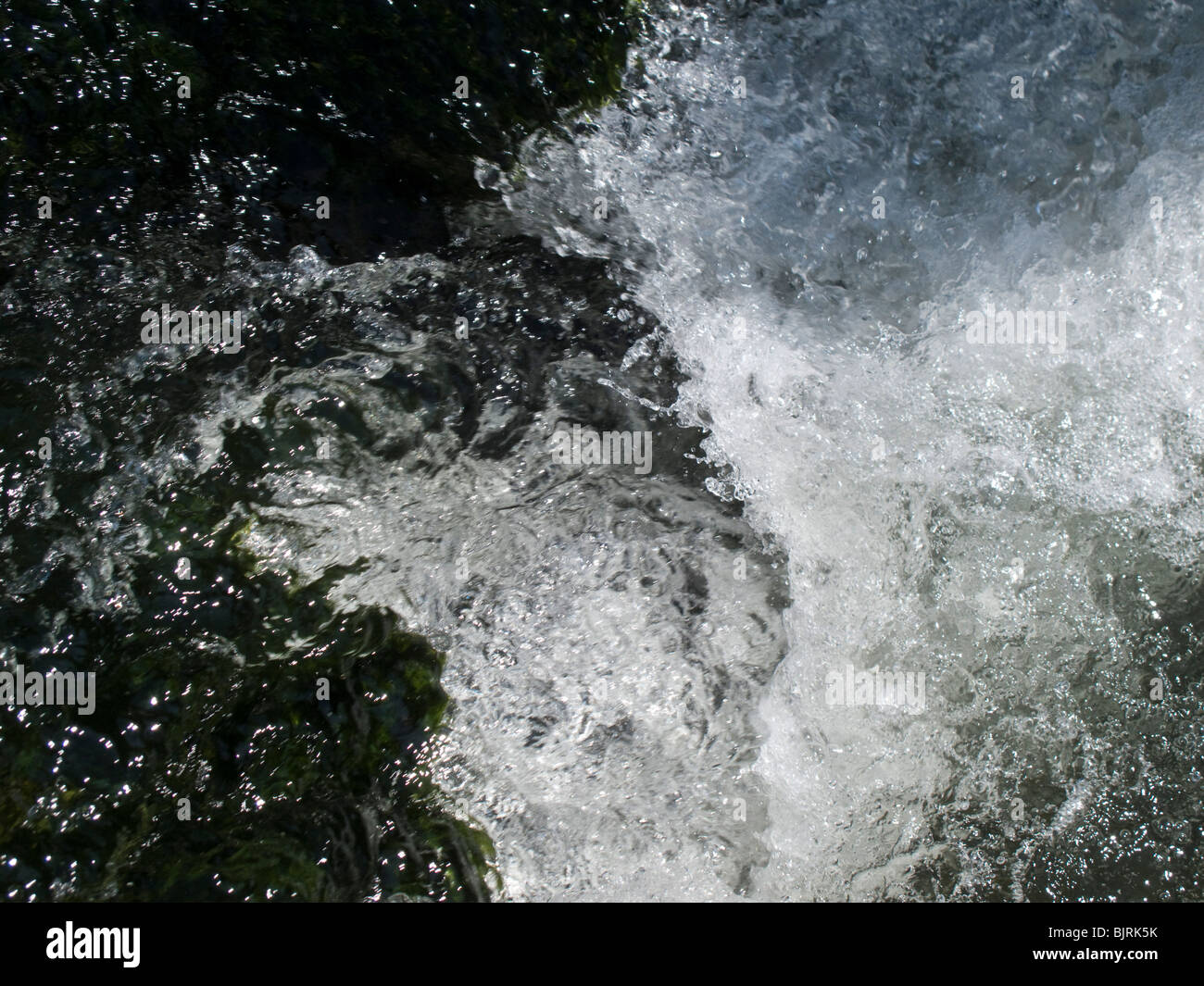 splashing sea water around rocks on a beach Stock Photo - Alamy