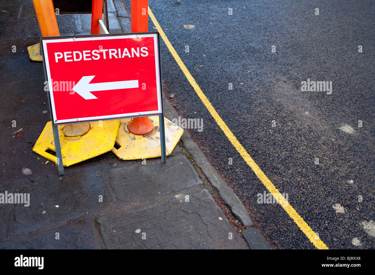 Red pedestrian sign on side of road with single yellow line Stock Photo ...