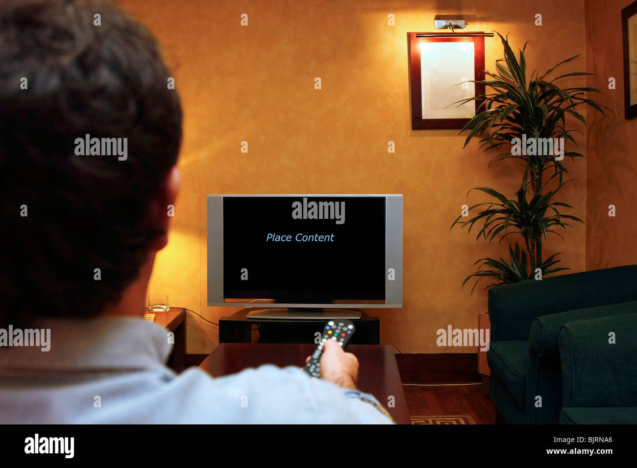 A man holding a remote control while watching TV. Empty space to place ...