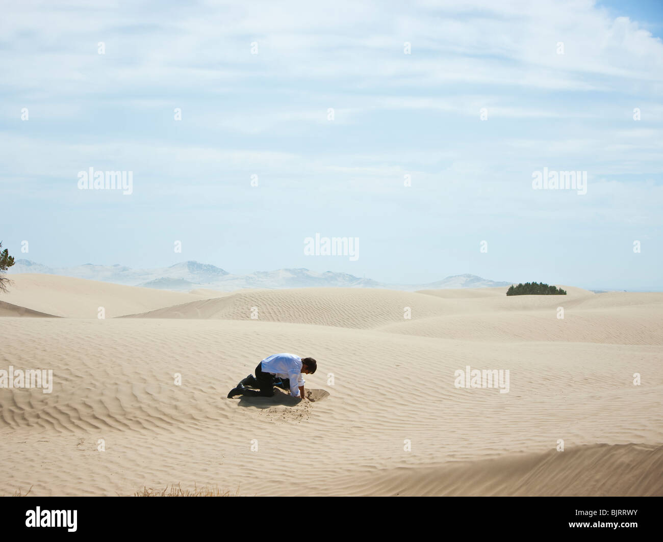 USA, Utah, Little Sahara, mid adult businessman digging hole on desert ...