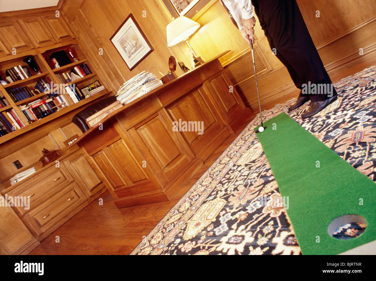 Executive putting golf ball in office Stock Photo - Alamy