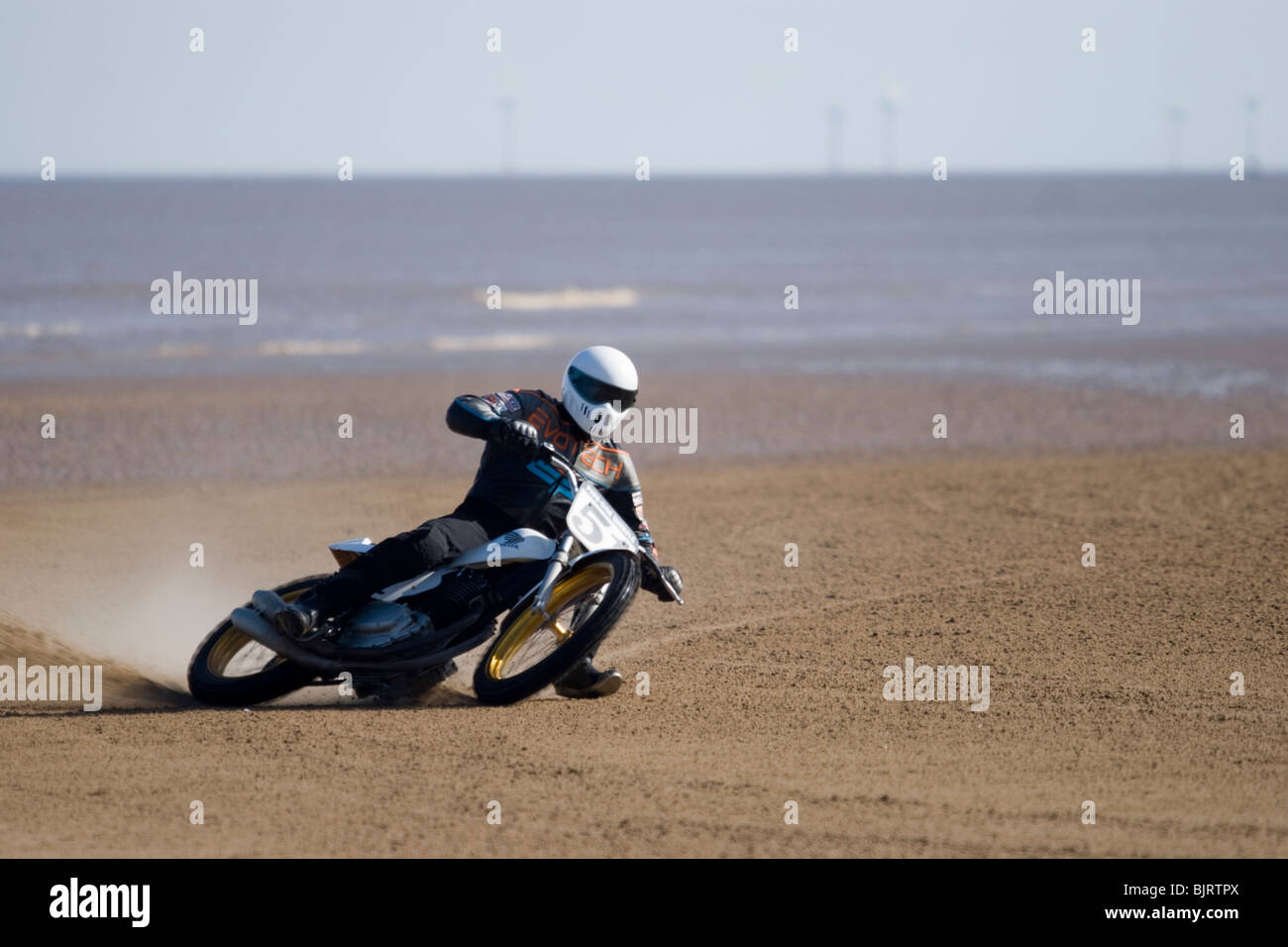 Motor bike sand racing on the beach with wind turbines in the ...