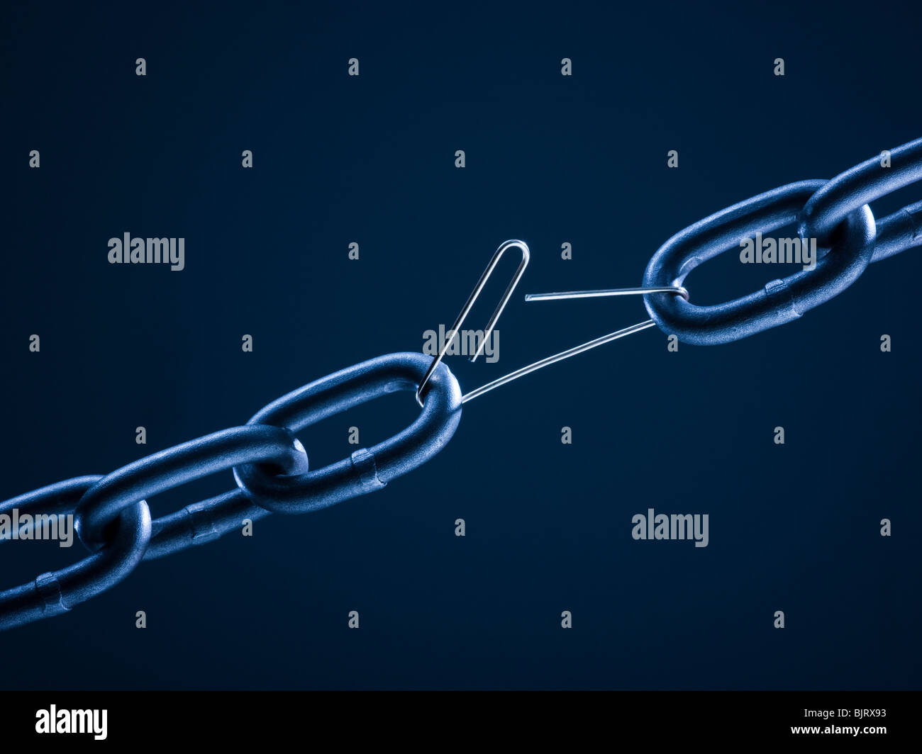 Chain linked with broken paper clip against blue background Stock Photo ...