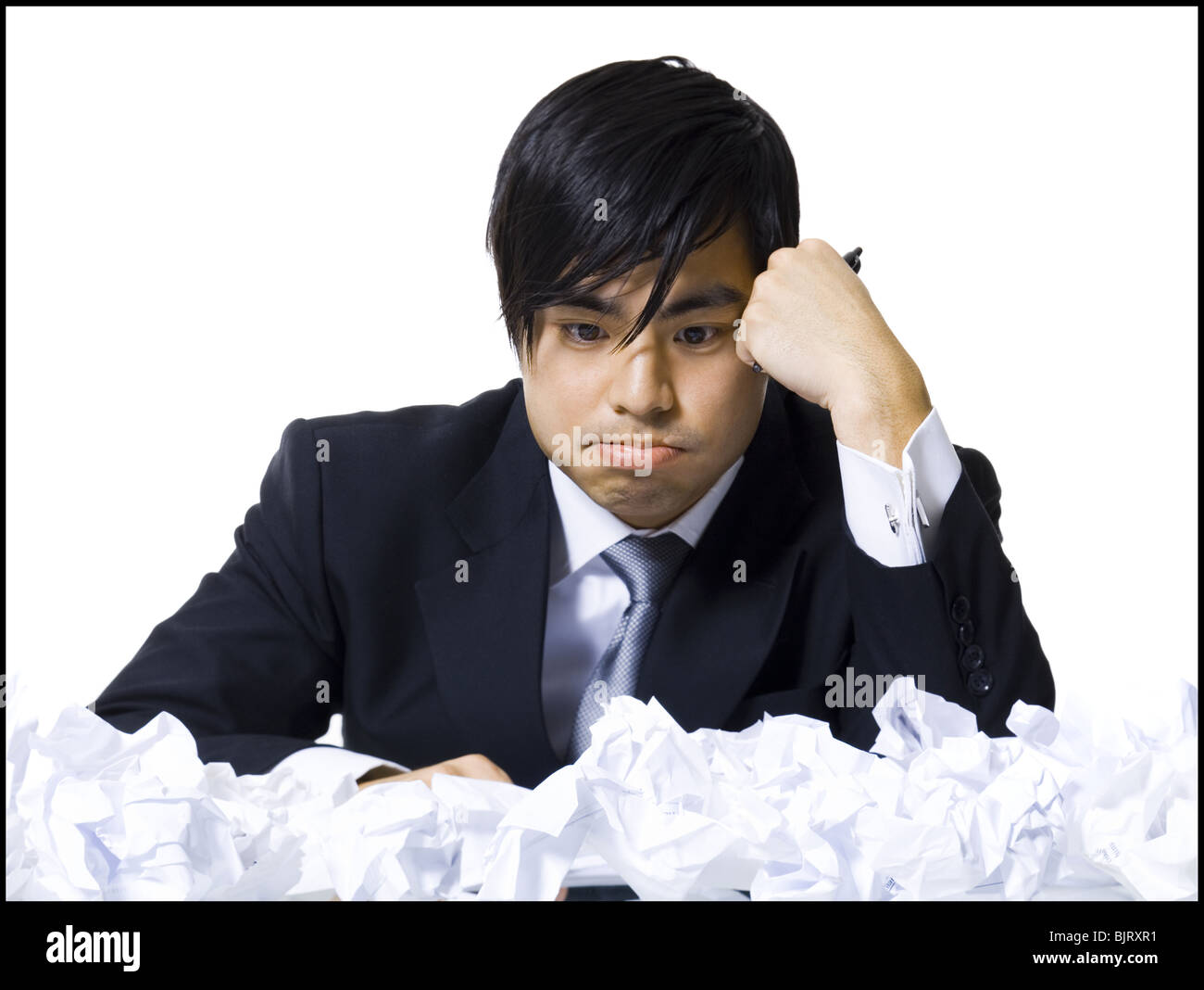 Frustrated businessman surrounded by crumpled papers Stock Photo - Alamy