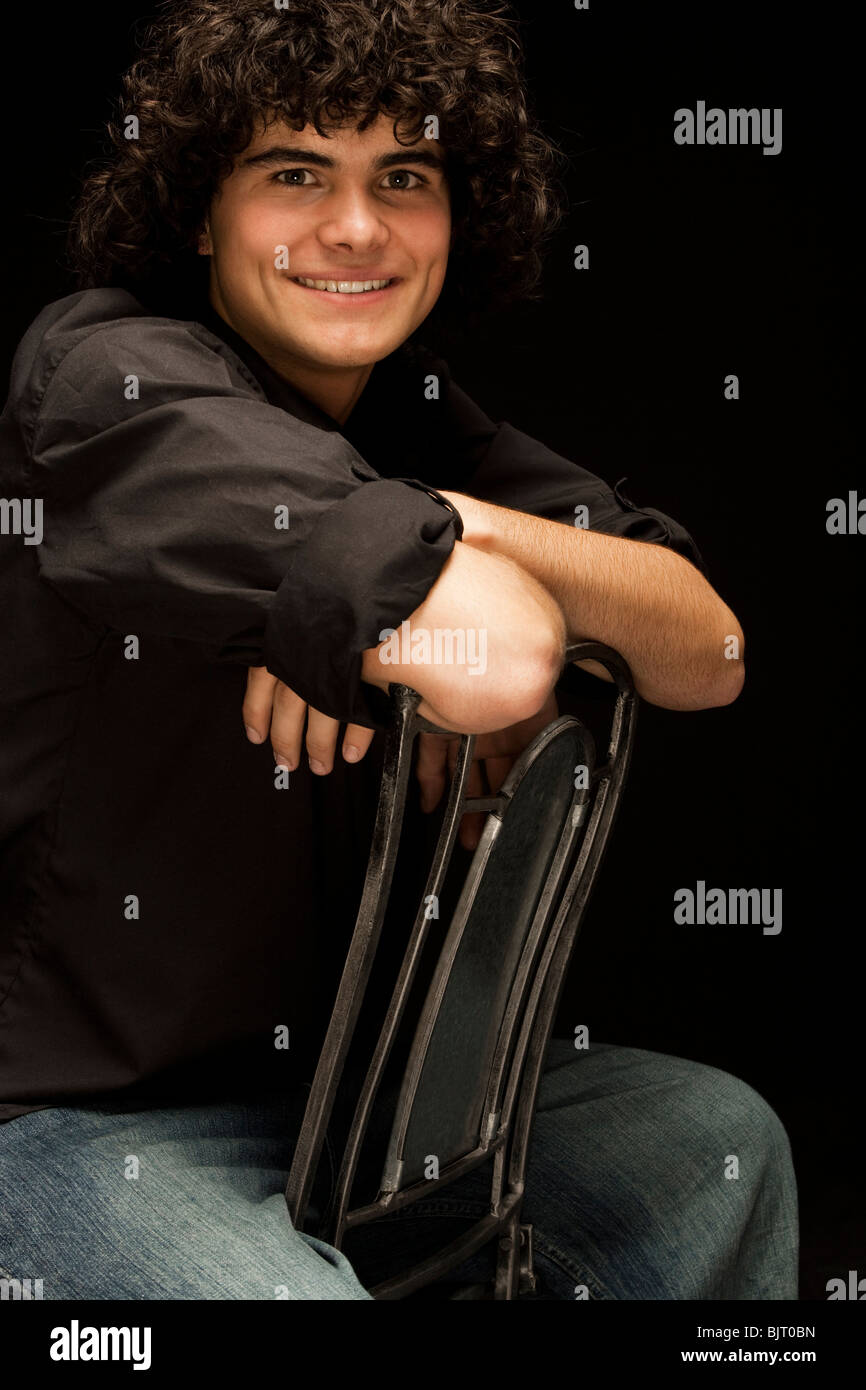Teenage boy (16-17) sitting backwards on chair, portrait Stock Photo ...