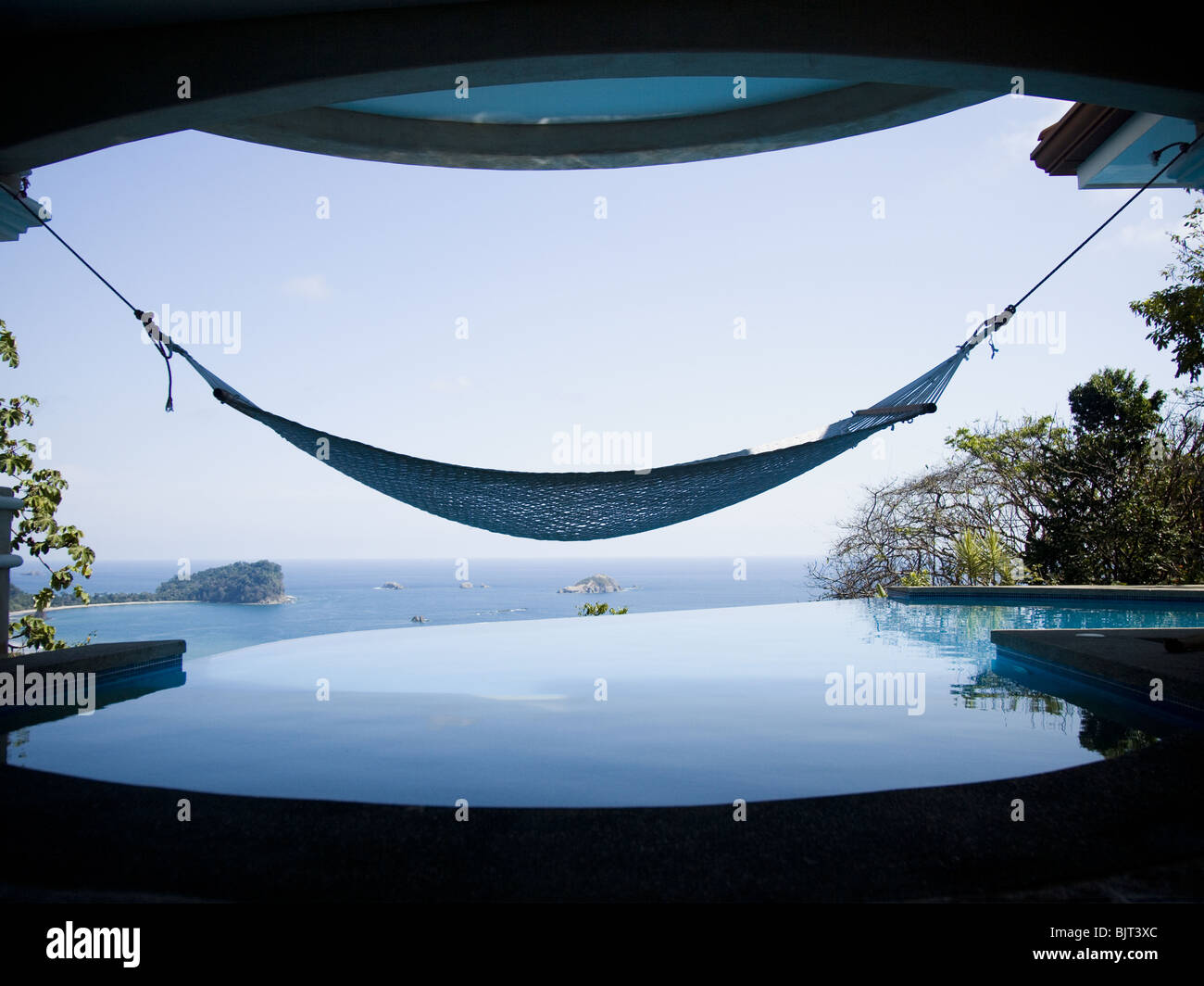 Man relaxing in a hammock overlooking infinity pool Stock Photo - Alamy