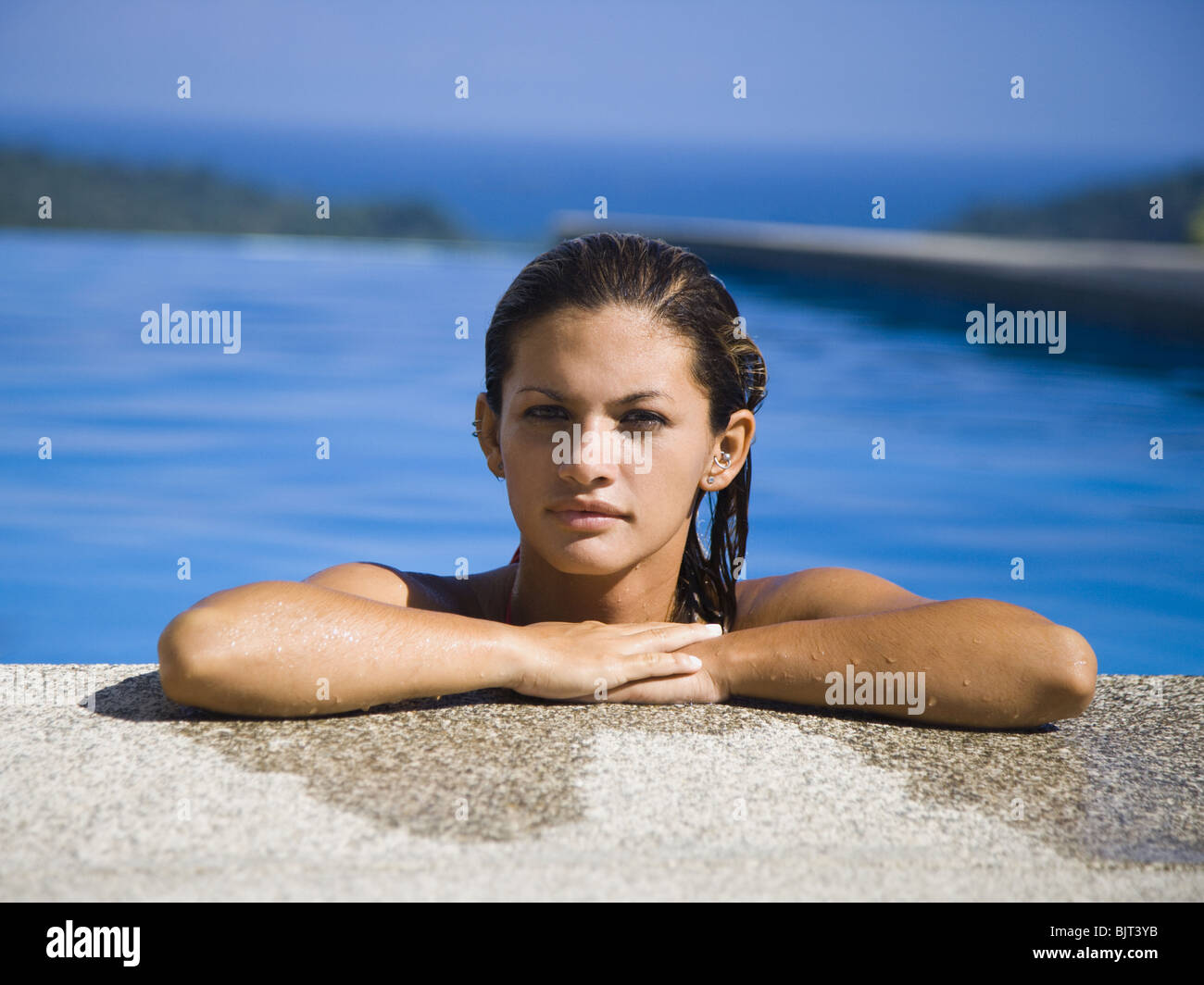 Woman resting on ledge of swimming pool Stock Photo - Alamy