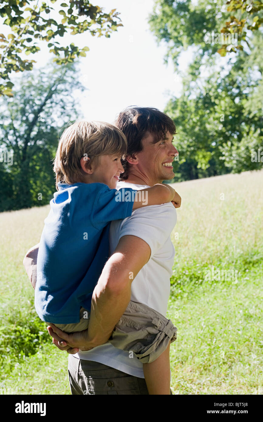 Father giving piggyback to son Stock Photo - Alamy