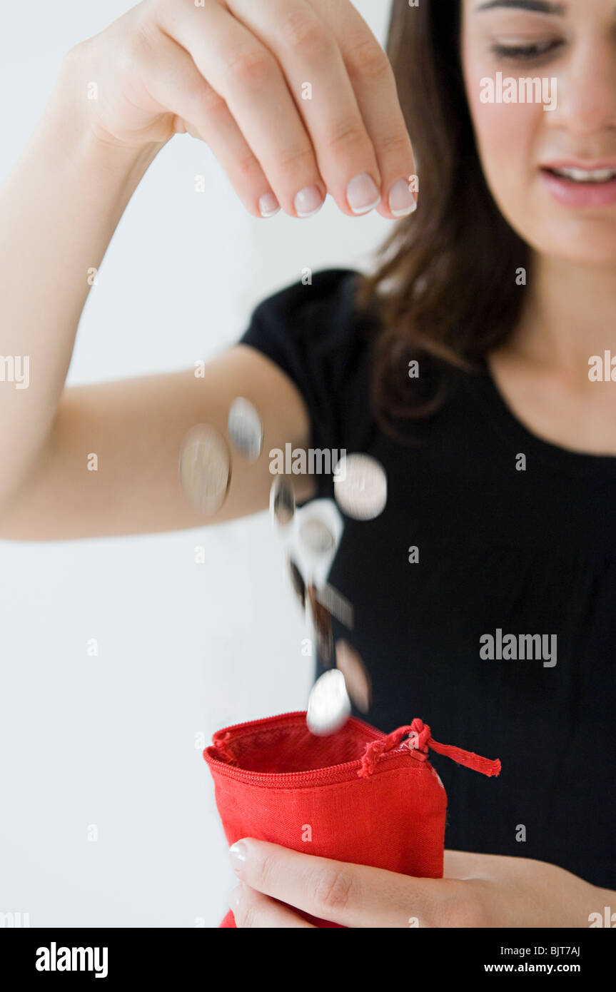 Woman dropping coins into purse Stock Photo - Alamy