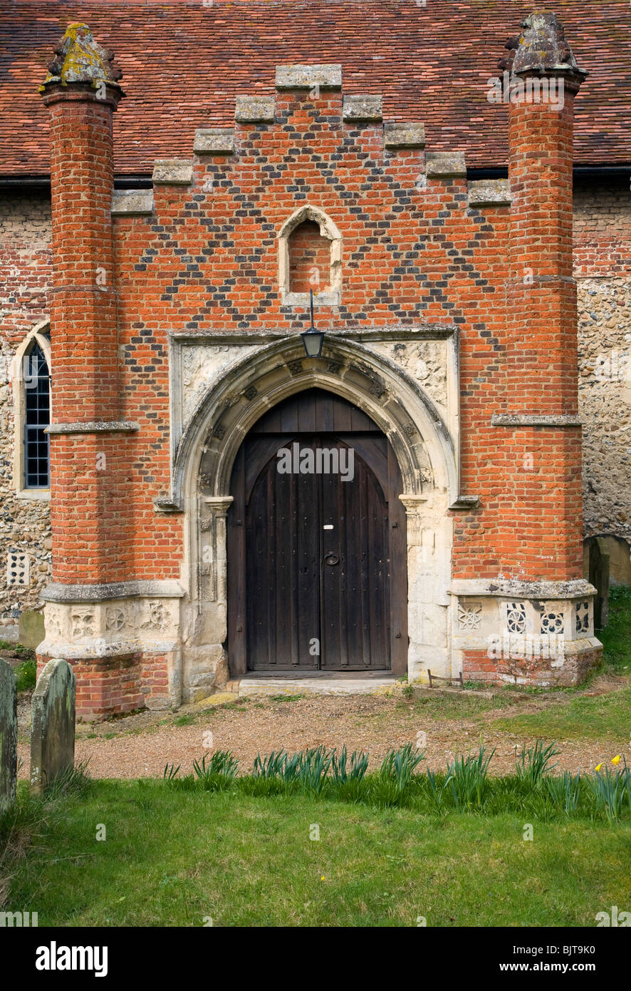 Tudor red brick porch set against more ancient building, St Peter's ...