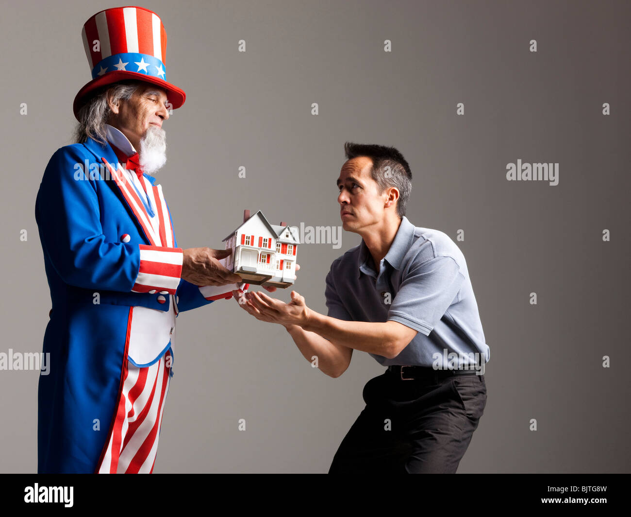 Man in Uncle Sam's costume giving model of house to other man, studio ...