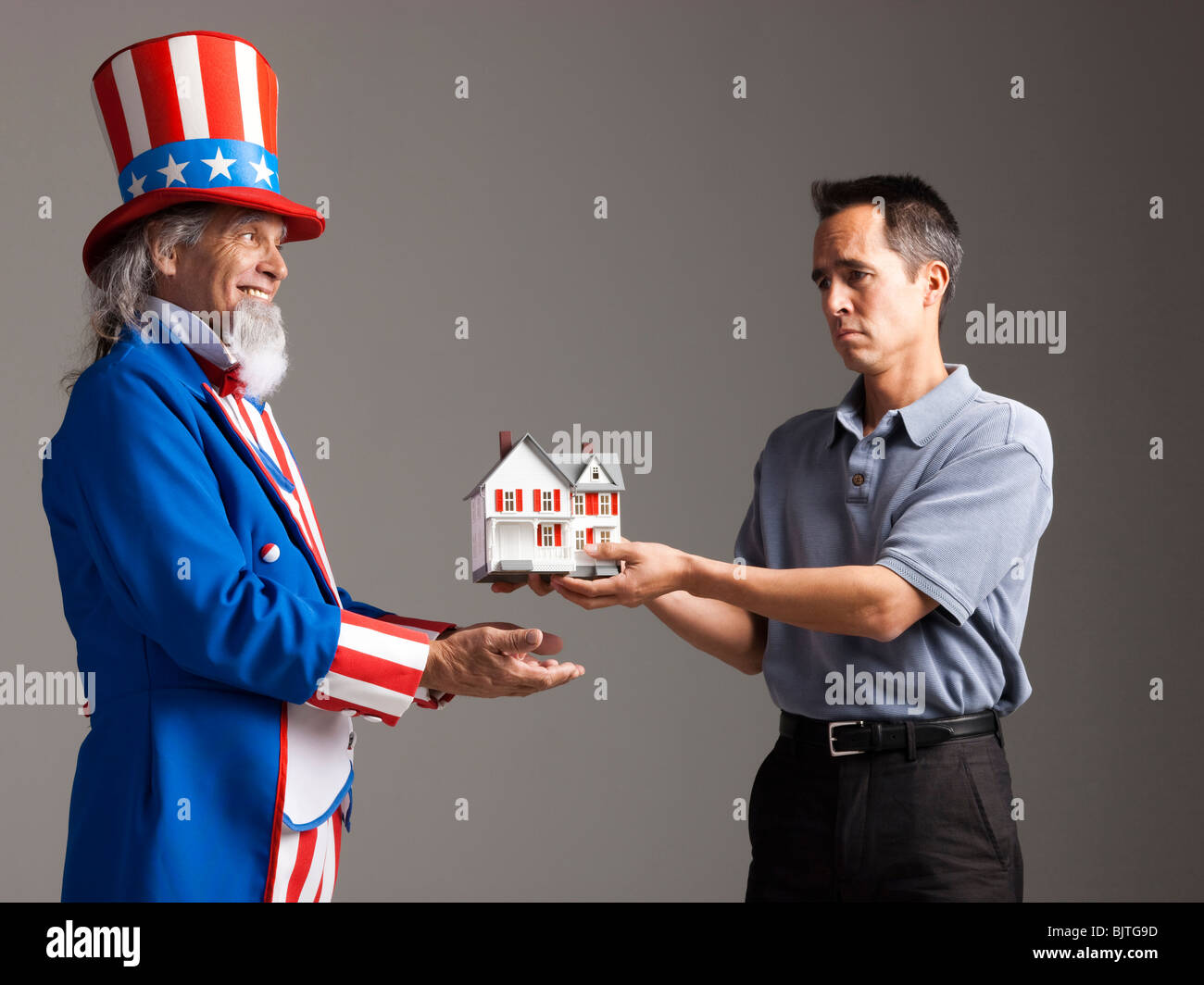 Man in Uncle Sam's costume giving model of house to other man, studio ...