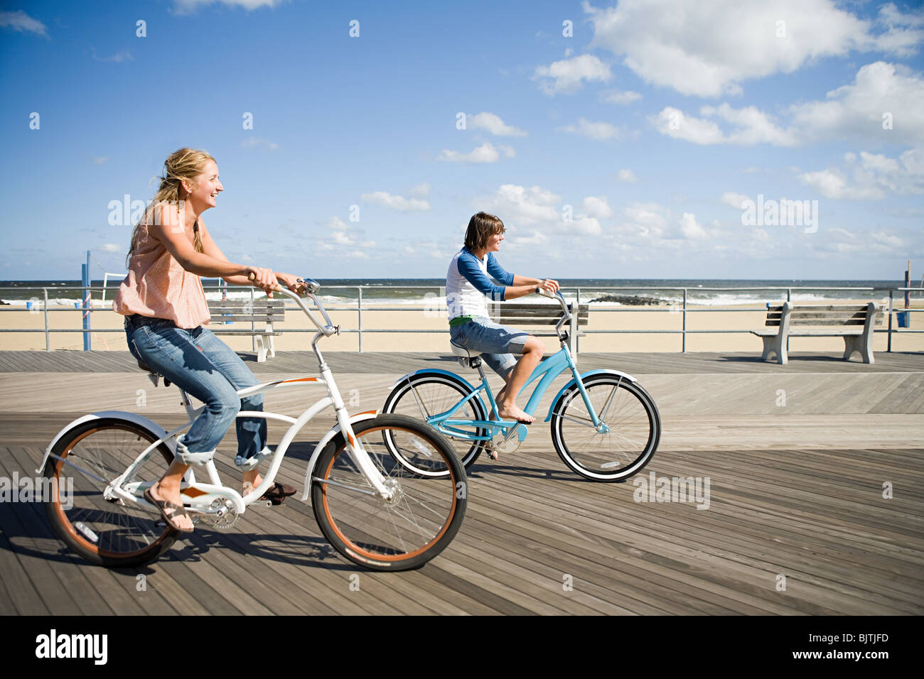 Two women cycling on boardwalk Stock Photo - Alamy