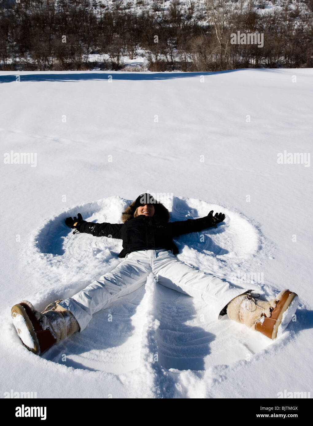 Woman making snow angel Stock Photo - Alamy