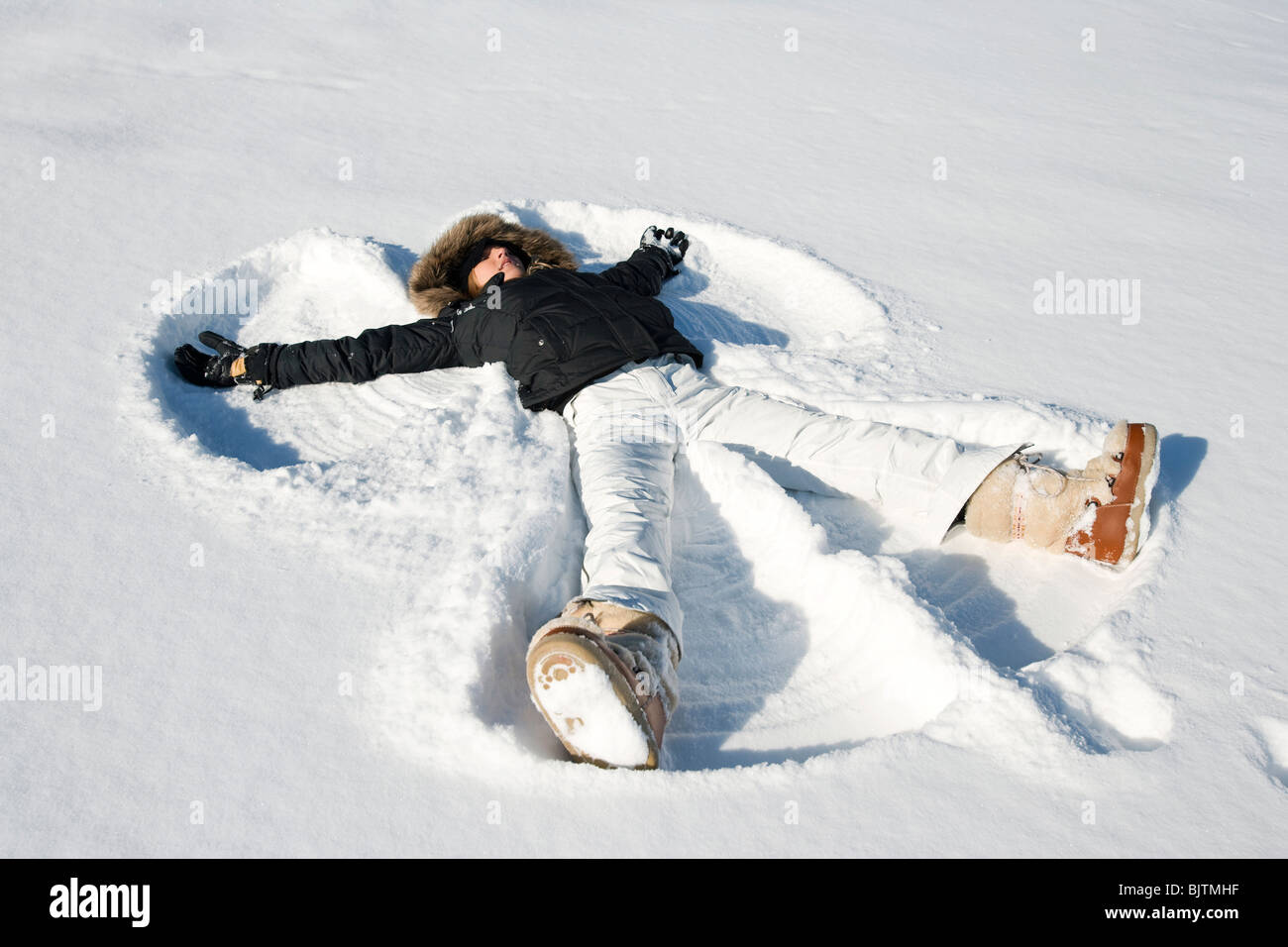 Woman making snow angel Stock Photo - Alamy