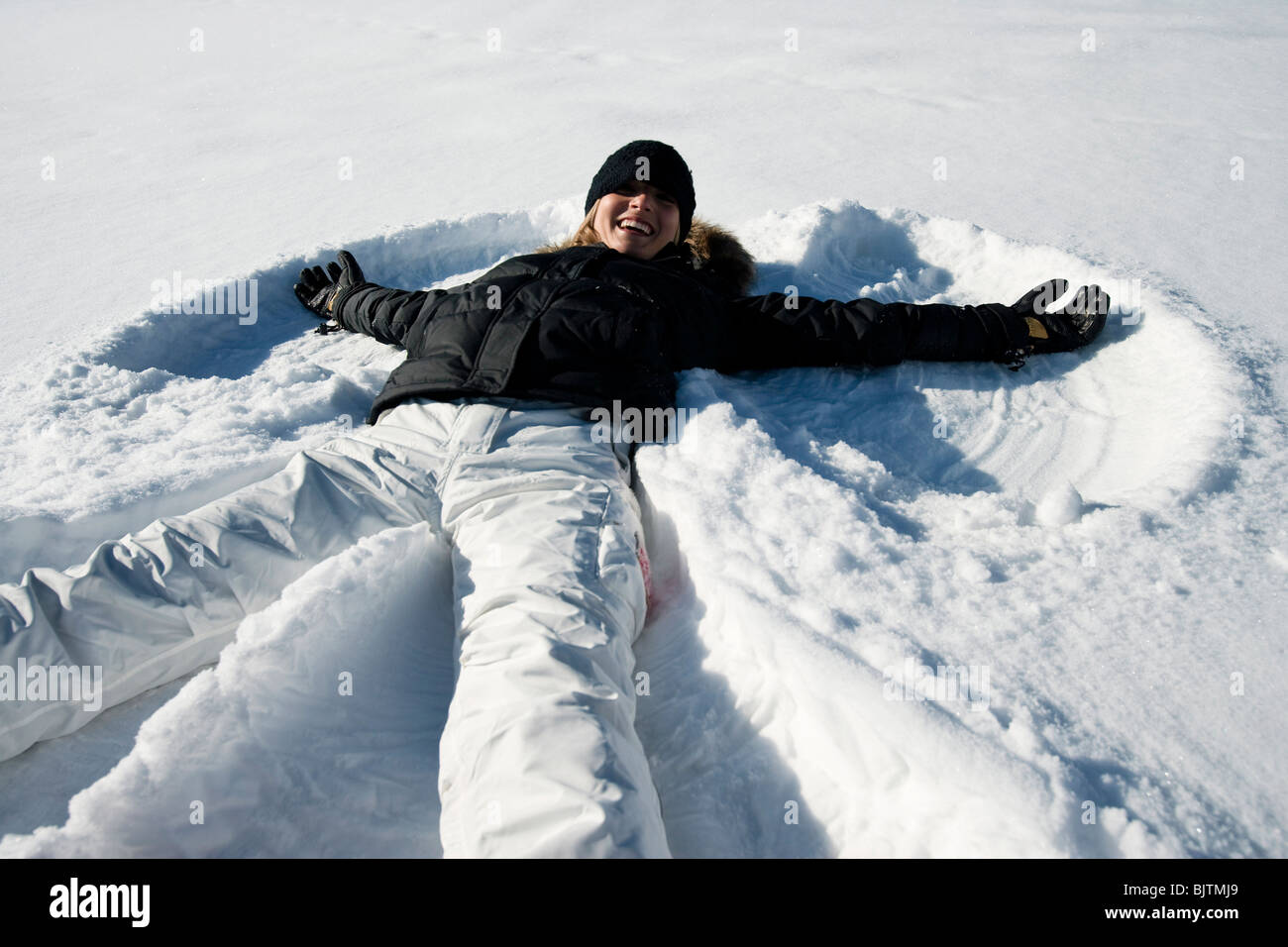 Woman making snow angel Stock Photo - Alamy
