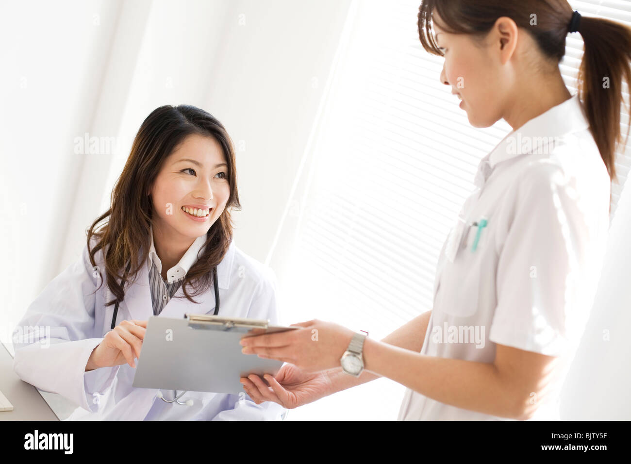 Female doctor discussing a medical chart with a nurse Stock Photo - Alamy