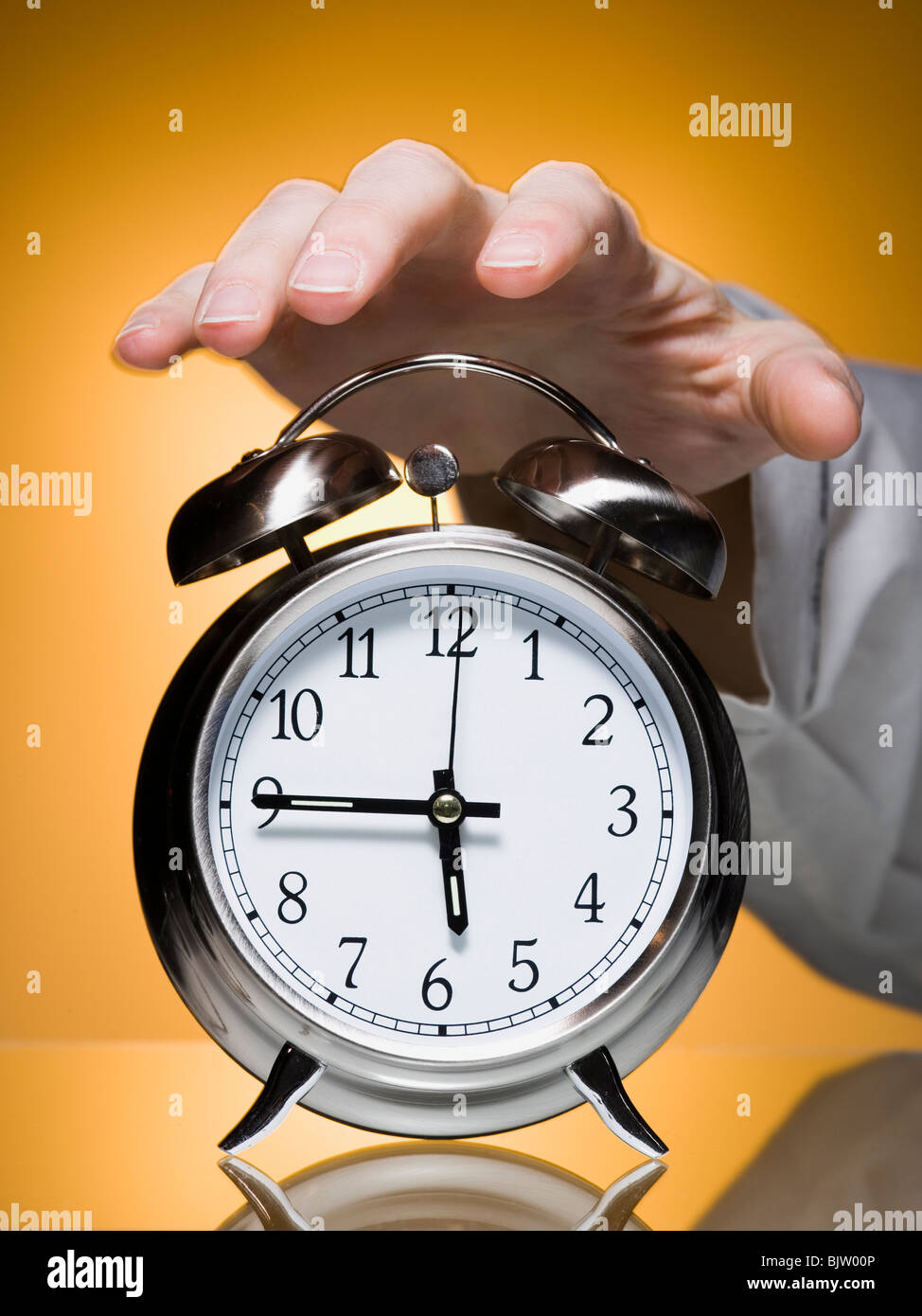 Hand reaching for alarm clock Stock Photo - Alamy