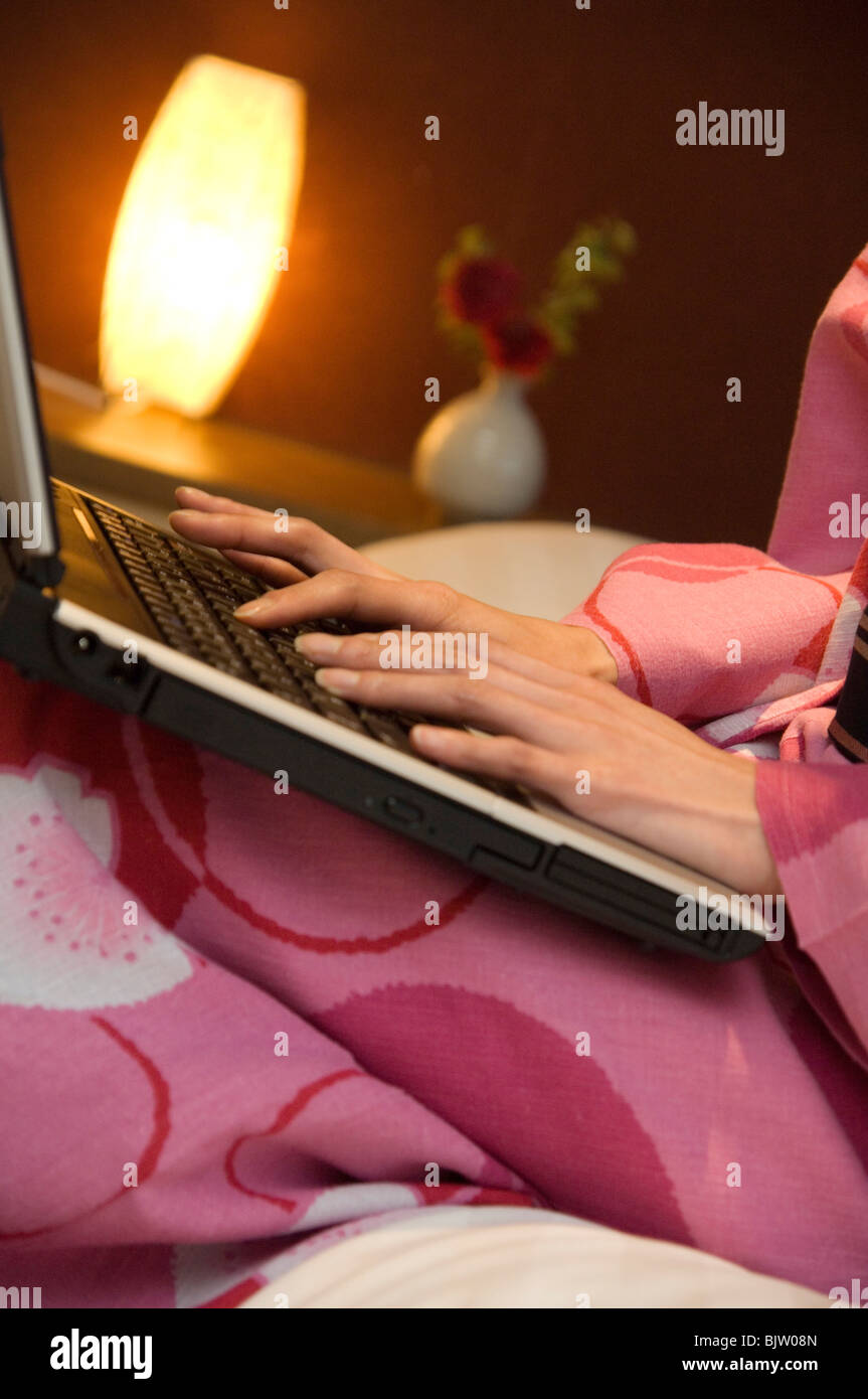 Women wearing yukata sitting on bed and typing on laptop Stock Photo ...